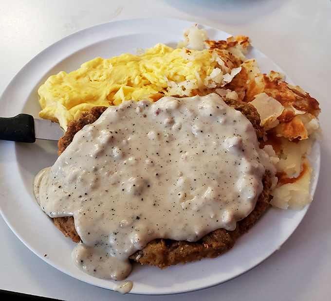Country fried steak smothered in gravy alongside eggs and hash browns – the breakfast equivalent of a warm hug from someone who truly loves you.