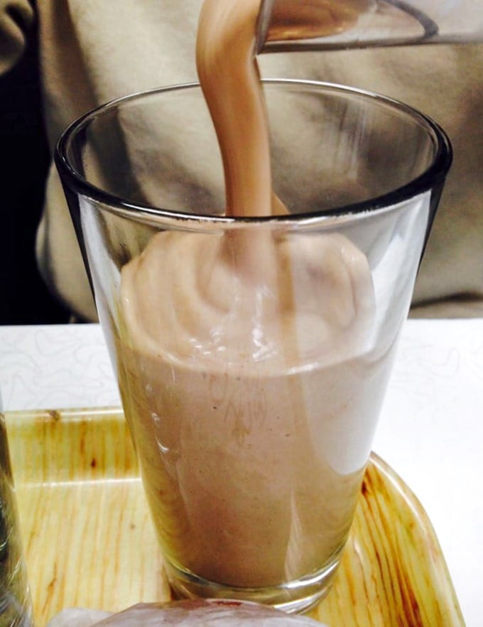 Chocolate milkshake being poured with the ceremony it deserves. Thick enough to respect your spoon but not so thick it gives your straw anxiety. 