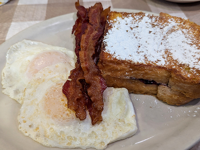 Breakfast perfection: French toast dusted with powdered sugar, eggs with just-right yolks, and bacon that should be in the Crispy Hall of Fame.