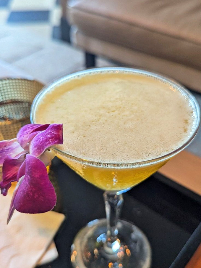 A cocktail garnished with an orchid that says, "Yes, I'm fancy, but I'll still knock your socks off with my perfectly balanced flavors."