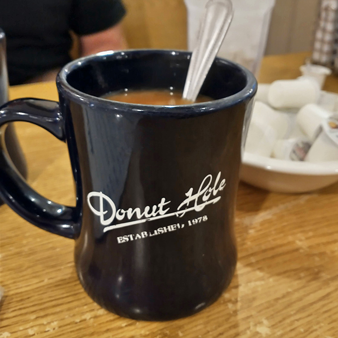 That navy blue mug isn't just holding coffee; it's holding the liquid courage needed to face a day of vacation activities with the in-laws.