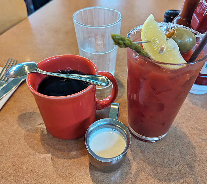 The perfect morning duo: a robust coffee in a cheerful red mug and a Bloody Mary garnished like it's wearing its Sunday best.