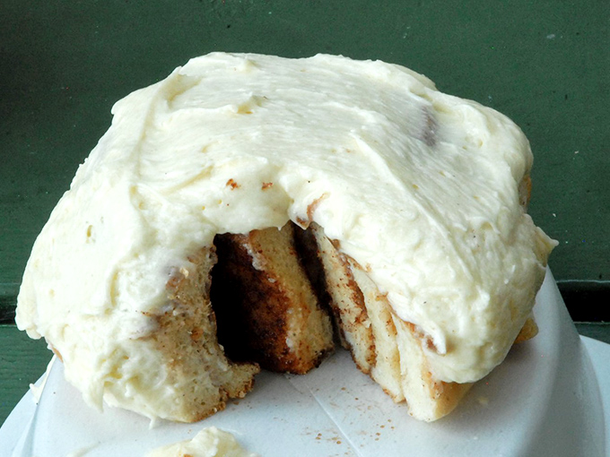 Cream cheese icing applied with such generous abandon that it transforms this cinnamon bun into something that defies polite eating techniques.