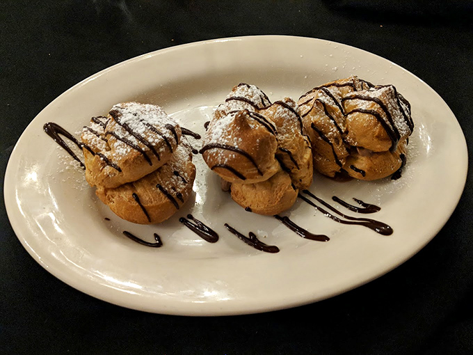 Cream puffs that defy gravity &ndash; light as air yet somehow substantial, drizzled with chocolate in a dessert that whispers rather than screams indulgence.