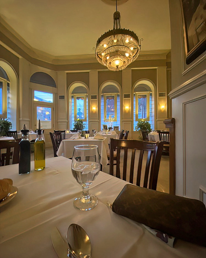The dining room's elegant chandelier and arched windows create an atmosphere where even your water glass feels slightly more sophisticated than usual.