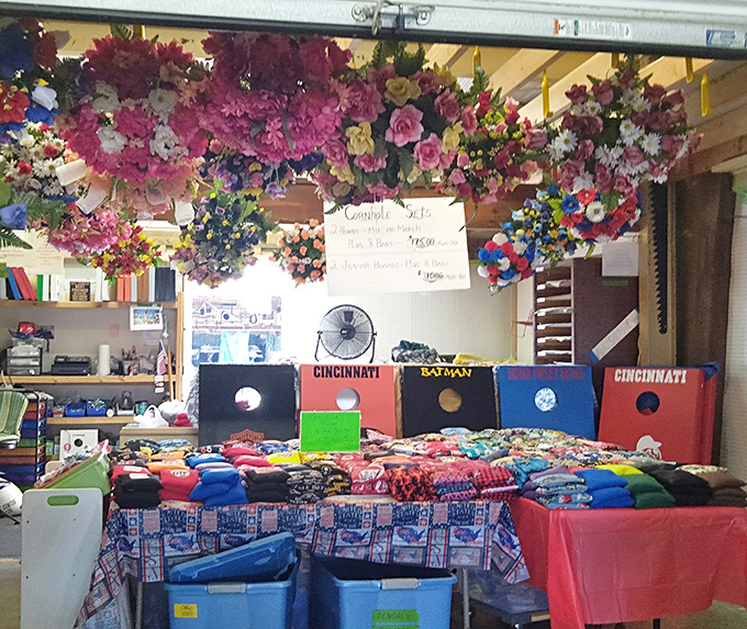 Artificial flowers cascade from the ceiling while sports-themed cornhole boards below create that perfect "only at a flea market" juxtaposition.