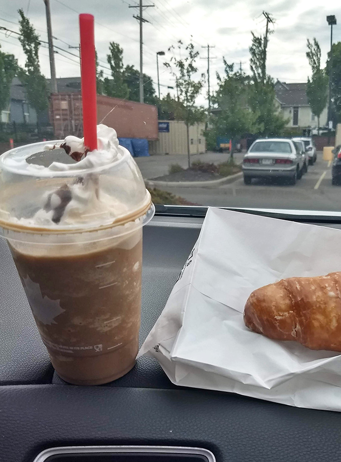 The perfect car dashboard still life: iced coffee and a fresh pastry, proving that sometimes the best dining room is wherever you happen to be.