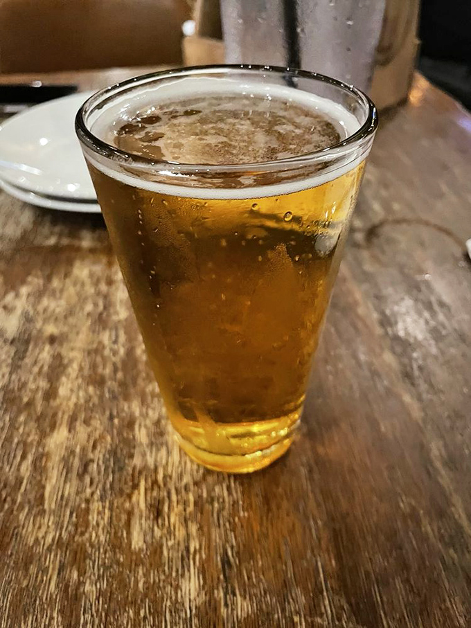 A cold beer on a wooden table&mdash;the perfect supporting actor in the barbecue drama unfolding on your plate. Simple pleasures, profound satisfaction.
