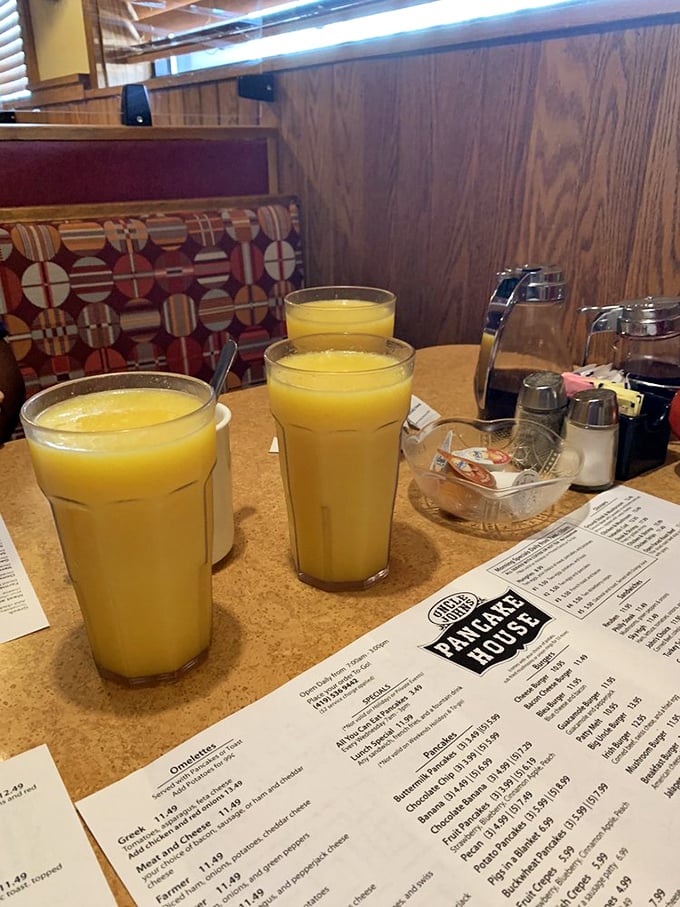 Tall glasses of orange juice stand at attention next to the menu &ndash; morning's perfect sidekick, ready to cut through the richness of breakfast indulgence.