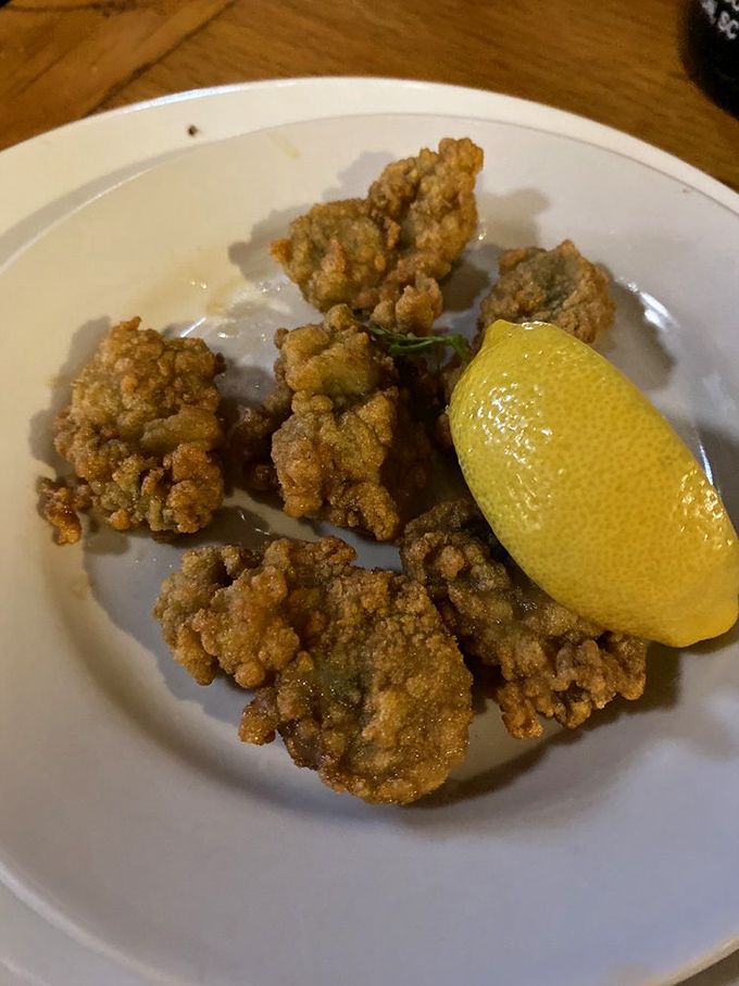 Fried oysters looking like crispy nuggets of ocean gold, with a lemon wedge standing by for that perfect squeeze of brightness.