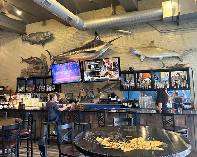 The bar area, where mounted fish silently judge your drink choices while bartenders craft the perfect maritime companion to your meal.