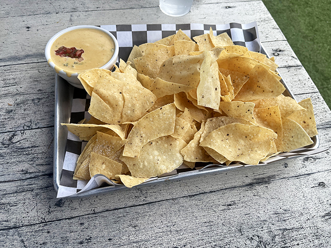 Nachos and queso—the diplomatic liaison between your appetite and the main event, served on a checkered paper that screams ‘trust me.
