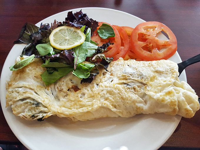 This isn't just an omelet; it's a fluffy yellow canvas painted with fresh ingredients and served with bagel soldiers for dipping.