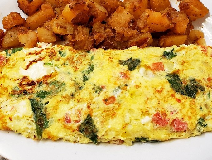 This isn't just an omelet—it's a perfect golden envelope delivering vegetables and cheese in every bite. Those home fries deserve their own zip code.