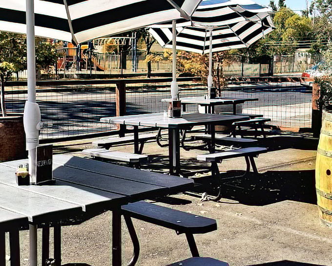 The outdoor seating area offers a sun-dappled respite for those patient enough to score a table. Black and white umbrellas provide shade for serious breakfast contemplation.