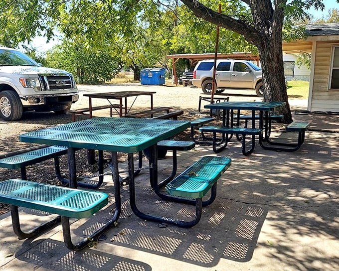 Outdoor seating under Texas skies where the shade trees and metal picnic tables create the perfect backdrop for burger bliss&mdash;nature's dining room.