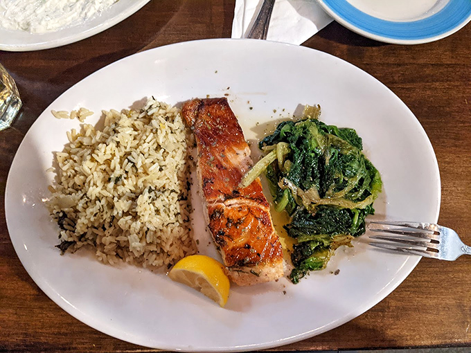 Simple yet spectacular: grilled salmon rests beside herb-flecked rice and saut&eacute;ed greens, proving that sometimes the most straightforward dishes deliver the most profound satisfaction.