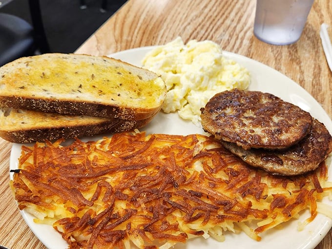 A hearty breakfast plate featuring golden hash browns, savory sausage, and thick-cut rye bread perfection.