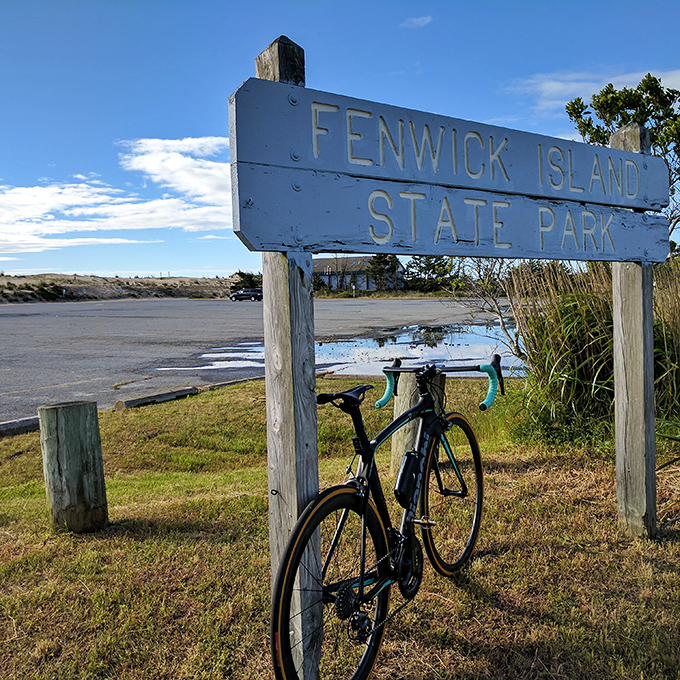 The park's wooden sign stands as a humble gatekeeper to natural wonders. Even bicycles pause to appreciate the view.