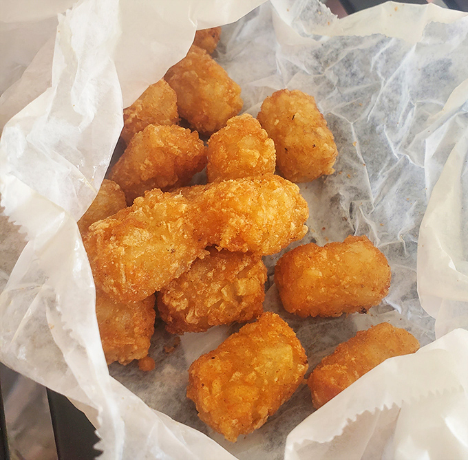 Golden-brown tater tots nestled in wax paper&mdash;childhood nostalgia with a crispy exterior and fluffy interior.