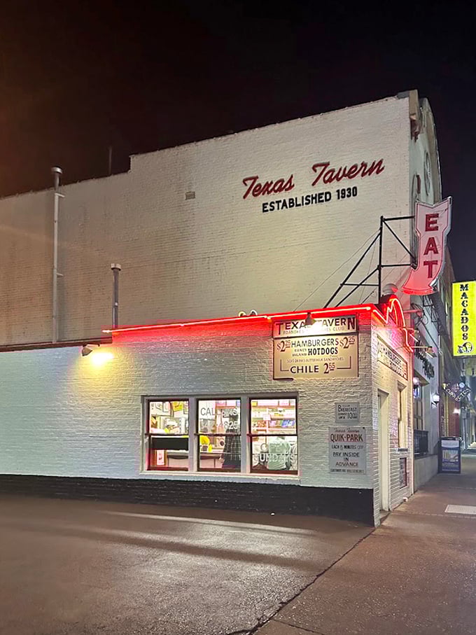 Neon signs and nighttime glow reveal a tiny brick institution where chili dogs have achieved legendary status.