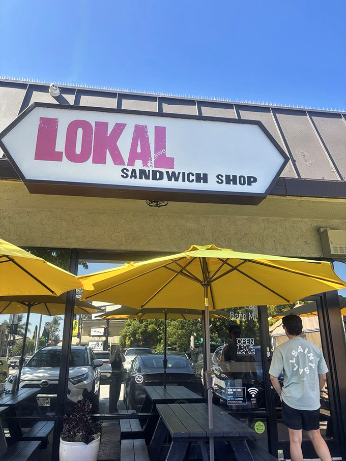 Those yellow umbrellas create instant sunshine, perfect for savoring sandwiches that taste like pure neighborhood joy.