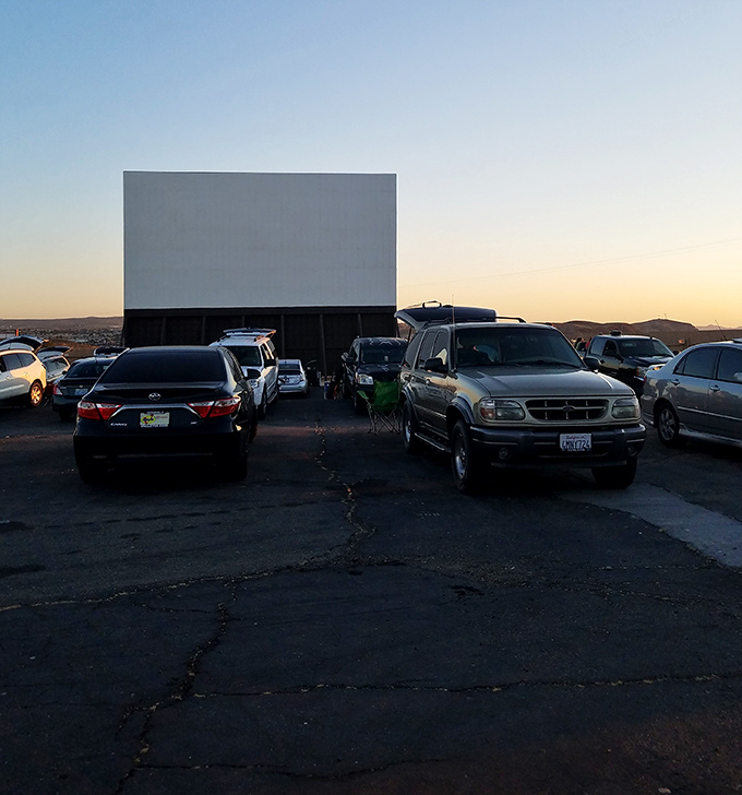Silver SUVs and cracked asphalt tell the story of Skyline Drive-in's enduring appeal, where desert sunsets provide the perfect opening credits.