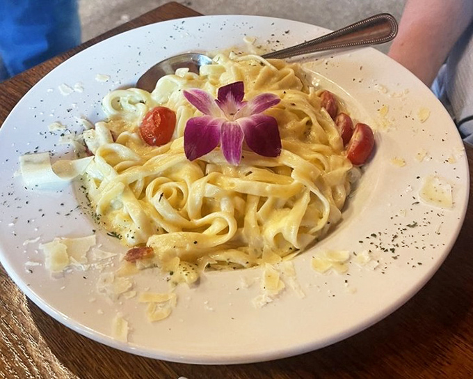 Fettuccine Alfredo garnished with an orchid—because sometimes pasta needs to dress up for dinner too.