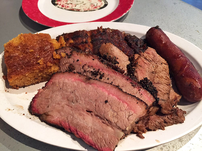 Barbecue's greatest hits album on a single plate—brisket showing off its smoke ring while cornbread stands by for sauce-sopping duty.