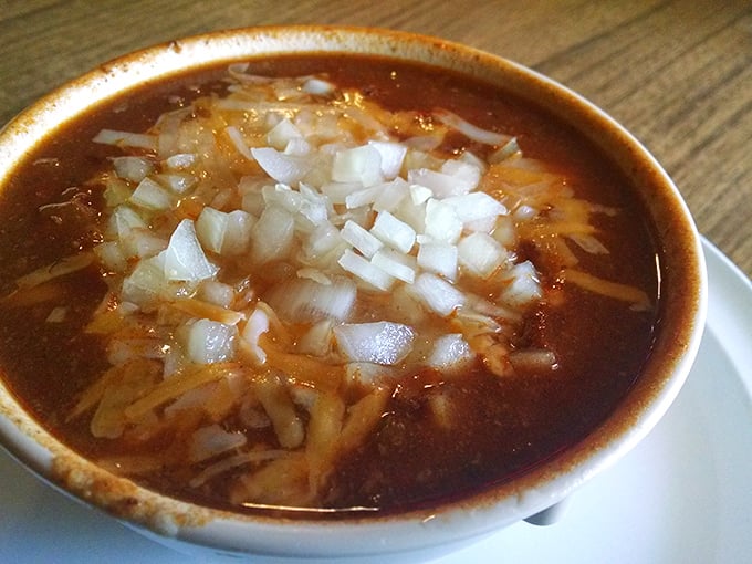 A bowl of chili topped with diced onions and melted cheese—winter comfort in liquid form that warms you from the inside out.