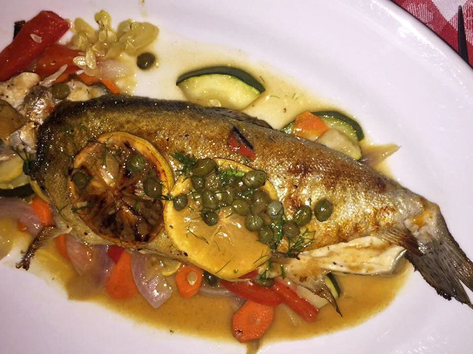 A whole branzino that looks like it swam directly from the Mediterranean to your plate, dressed simply with lemon, capers, and vegetables.