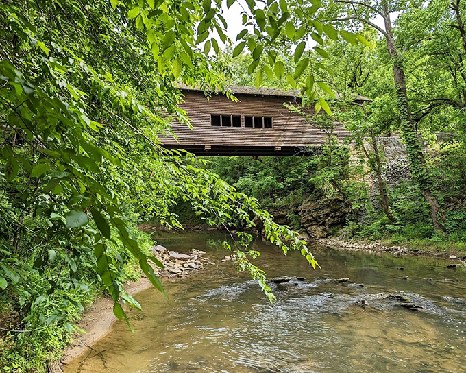 Nature frames her own masterpiece. The bridge seems to float above the water, a wooden time capsule suspended between centuries of Tennessee history.