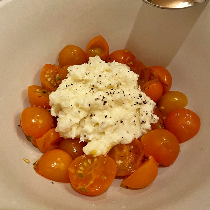 Cherry tomatoes surround creamy burrata like devoted admirers &ndash; a simple combination that proves sometimes less really is more.