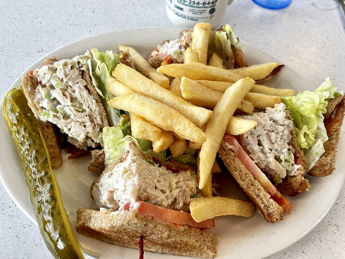 The club sandwich—a three-story monument to lunch perfection with crisp fries and a pickle spear that's not just a garnish, but a necessity.
