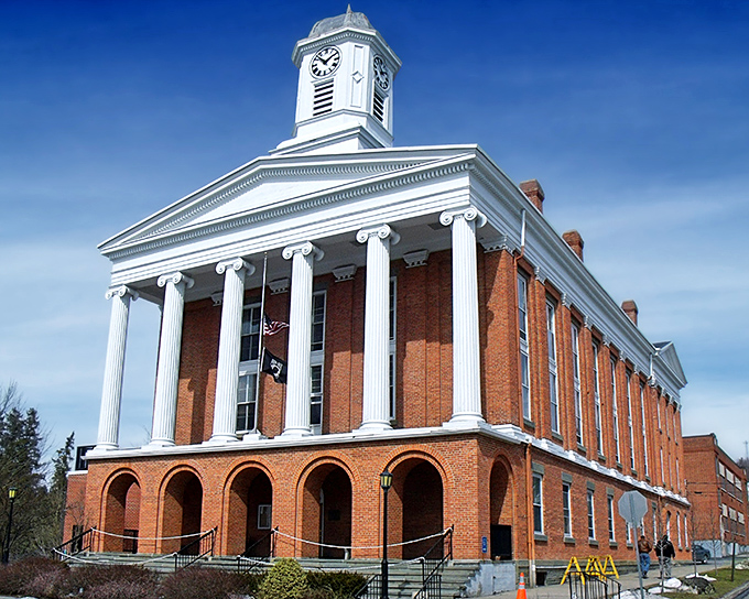 Classical columns and red brick courthouse architecture commands respect while maintaining welcoming small-town accessibility and charm.