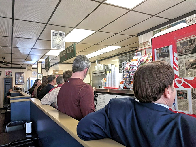 The lunch counter ballet: customers in suits and casual wear alike, united in the democratic pursuit of sandwich excellence.