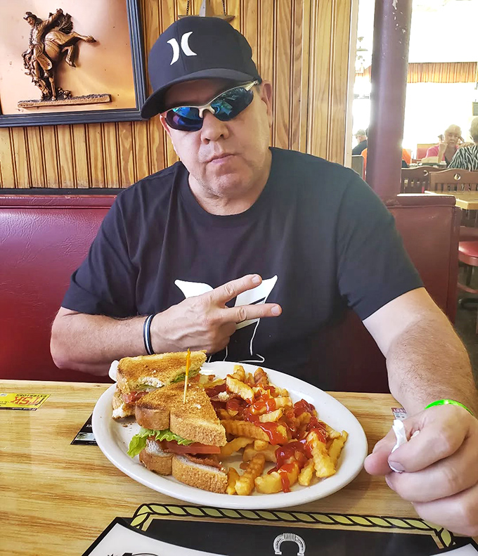 A satisfied diner pointing to his club sandwich. That expression says everything about Rodeo Diner's satisfying comfort food.