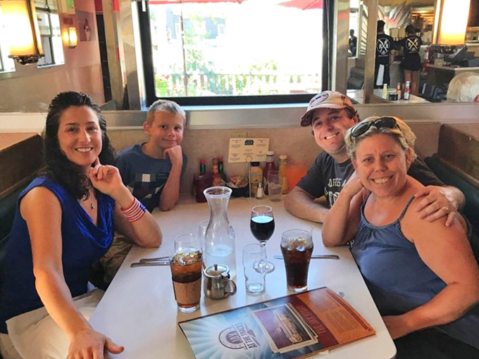 Happy diners gathered around beverages and conversation &ndash; the universal language of a great meal shared with people you love.