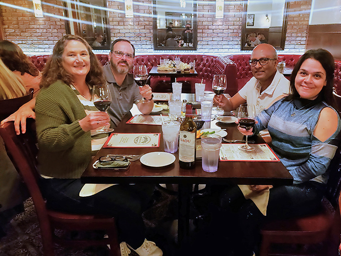 The universal language of "this food is amazing" spoken through raised wine glasses. These diners aren't just eating dinner&mdash;they're creating memories around that bottle of red.
