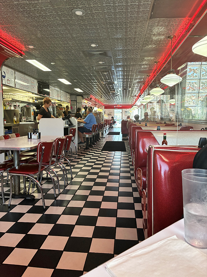 The diner's interior stretches like a runway of red vinyl and chrome, where breakfast dreams come true under pressed tin ceilings.