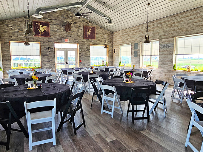 The dining room dressed in black and white, with sunlight streaming through windows framing countryside views &ndash; farmhouse elegance without pretension.