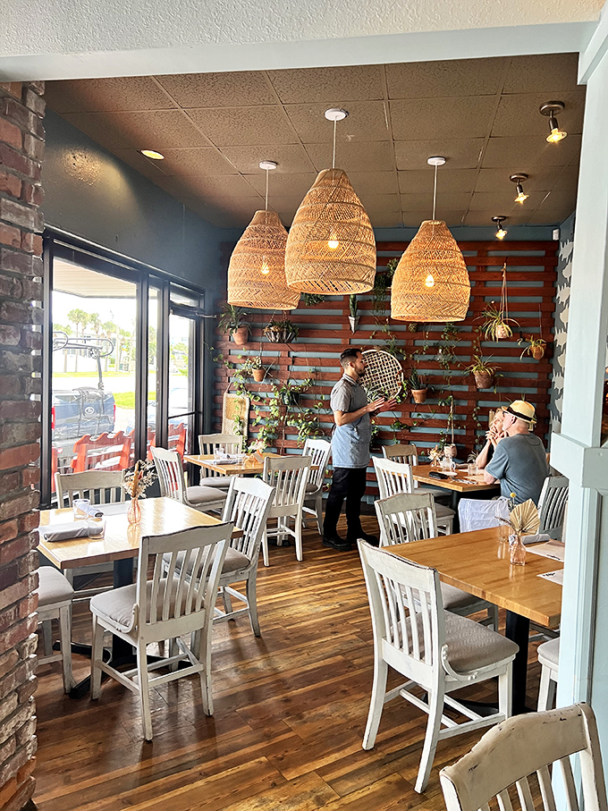 Woven pendant lights cast a warm glow over diners, while the plant wall brings the outside in. Coastal dining doesn't get more inviting than this.