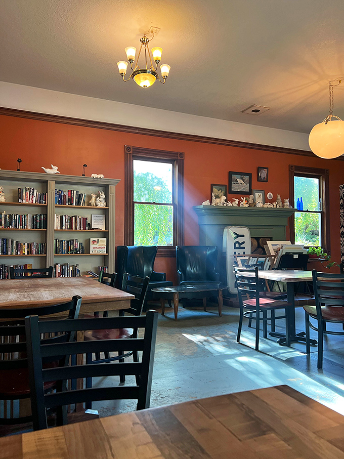 Sunlight streams through windows onto wooden tables, bookshelves, and terracotta walls—creating a space that feels more like a beloved community living room than a bakery.