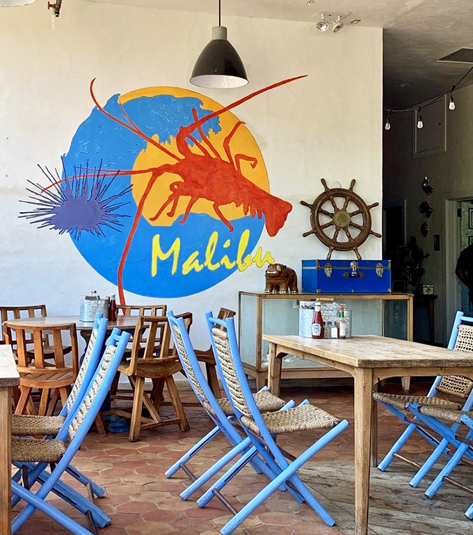 The vibrant mural featuring a lobster against a sunny backdrop captures Malibu's laid-back coastal energy, while wooden ship wheels remind you of the ocean's bounty just outside.