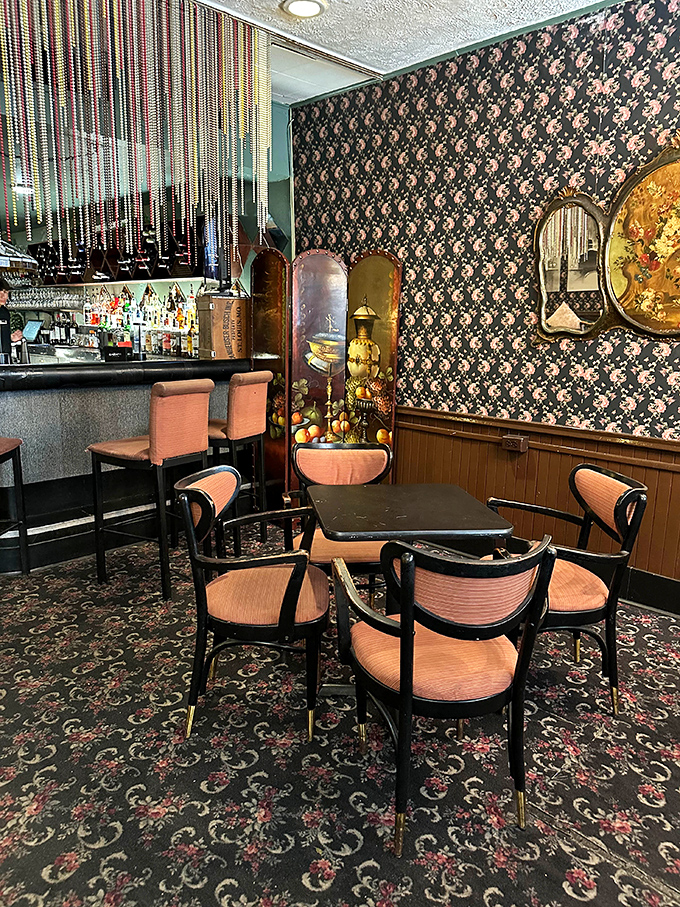 The bar area feels like stepping into a 1960s film set &ndash; patterned wallpaper, vintage dividers, and coral chairs creating a retro cocktail oasis.