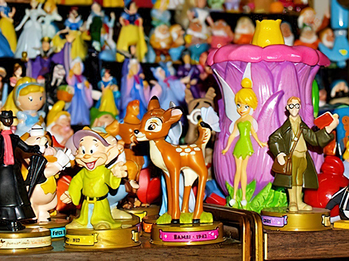 Disney figurines standing at attention like tiny animated ambassadors. Bambi and Tinkerbell never expected to share the same shelf space.