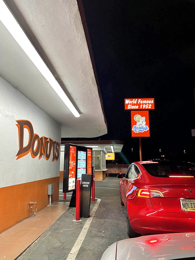 The drive-through at night: where late-night cravings meet convenience under the watchful eye of that iconic donut silhouette.