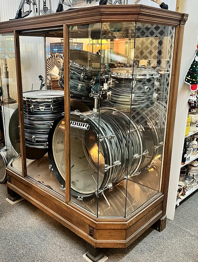 A drum set frozen in time, displayed like the rock star it once was. Someone's garage band dreams preserved behind glass.