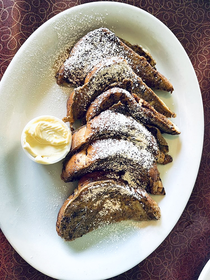 French toast dusted with powdered sugar&mdash;thick-cut and custardy in the middle, with a side of butter that's already surrendering to the warmth.