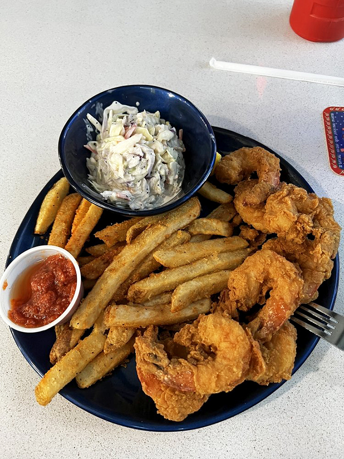 Golden-fried shrimp and crispy fries share the spotlight with creamy coleslaw—the holy trinity of seafood shack perfection that never goes out of style.